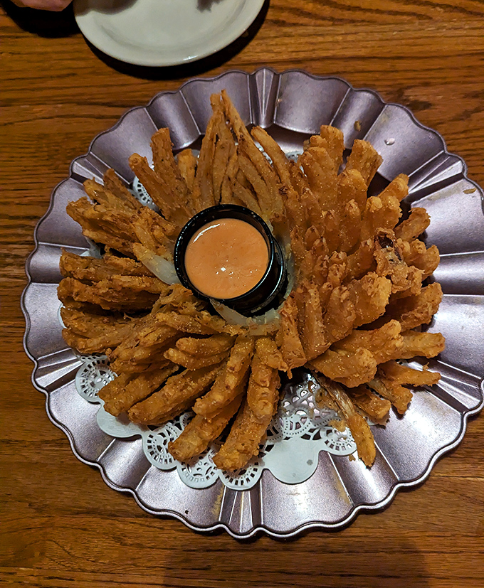 The Onion Flower blooms on your table like a golden crispy sculpture, with dipping sauce as its perfect companion.