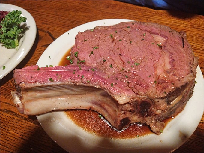 The prime rib bone extends beyond the plate like nature's own handle, designed for the serious business of meat appreciation.