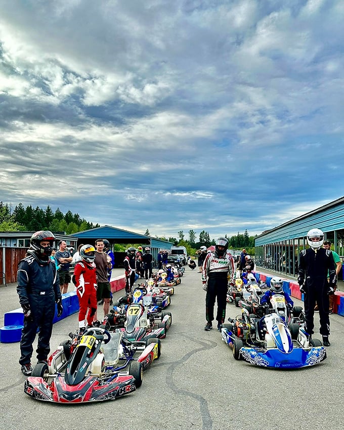 The pre-race huddle: where weekend warriors in racing suits discuss strategy while secretly wondering if they remembered to stretch.