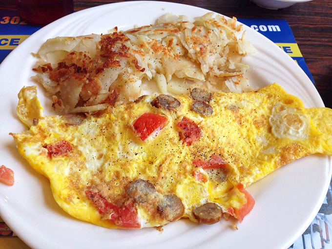 Breakfast perfection on a plate: a fluffy omelet studded with savory treasures alongside home fries that achieve the golden-crisp ideal.