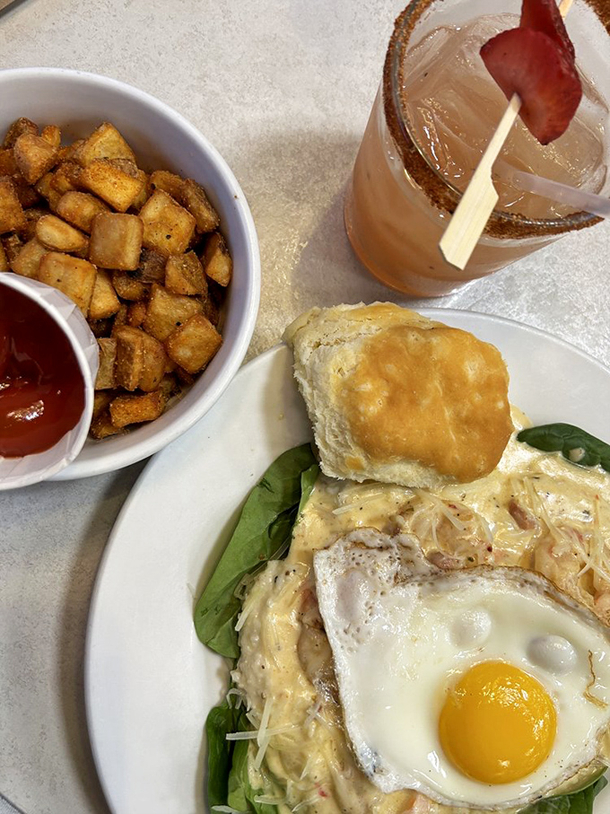 Breakfast alchemy at its finest—creamy grits, scrambled eggs, and crispy chicken create the holy trinity of morning indulgence. That pink drink is just showing off.