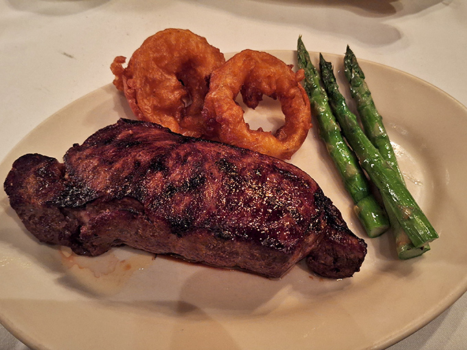 A perfectly seared steak flanked by golden onion rings and vibrant asparagus. This plate has more balance than a tightrope walker with an inner ear implant.