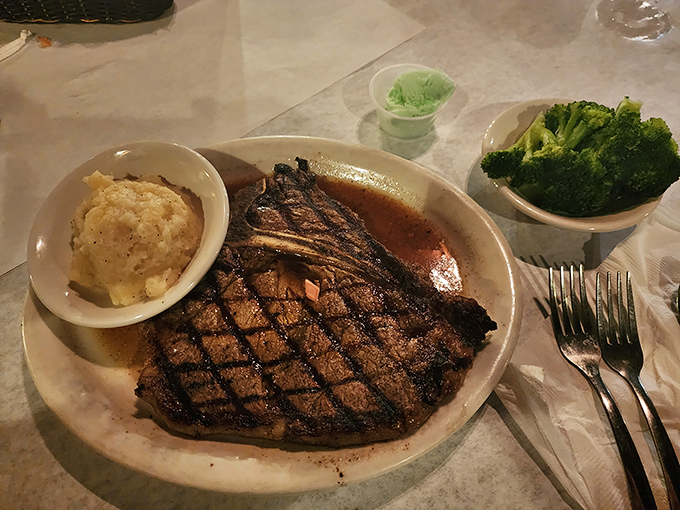 T-bone steak, mashed potatoes, and broccoli: the holy trinity of steakhouse religion, presented with reverence on a simple white plate.