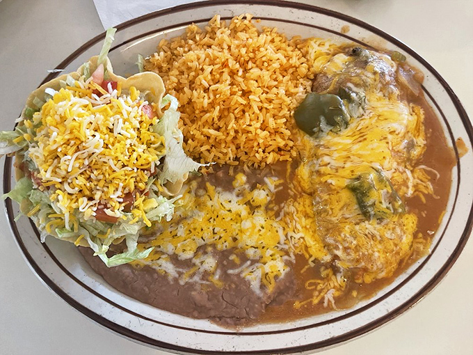 The holy trinity of Mexican comfort: a crispy tostada, cheese-draped enchilada, and fluffy rice. This plate doesn't just feed you&mdash;it hugs you from the inside.