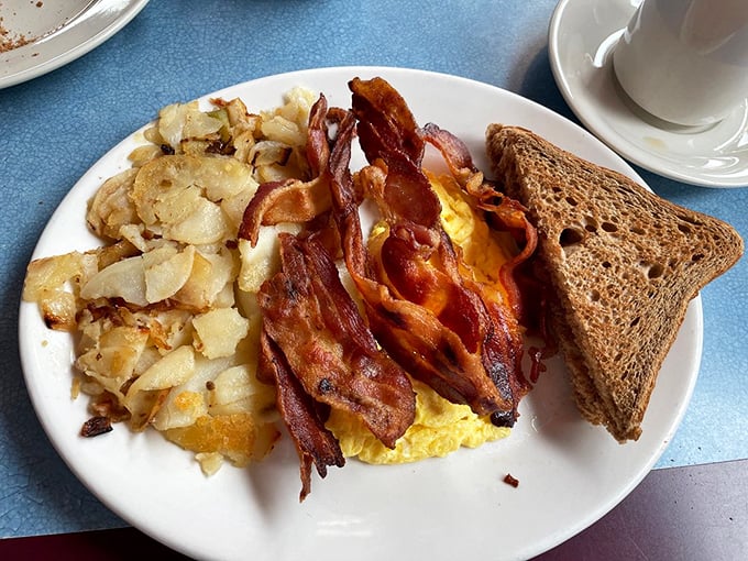 The holy trinity of breakfast: crispy bacon, fluffy eggs, and golden home fries&mdash;a plate that says "good morning" better than words ever could.