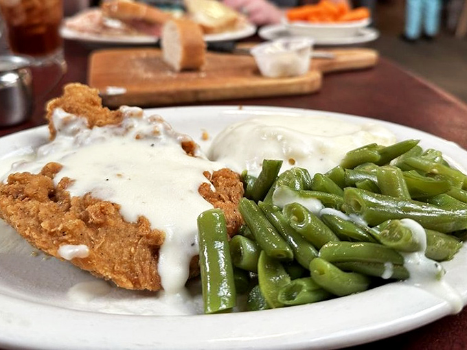 Country fried steak swimming in gravy with green beans on the side&mdash;the kind of plate that makes cardiologists wince and souls sing.