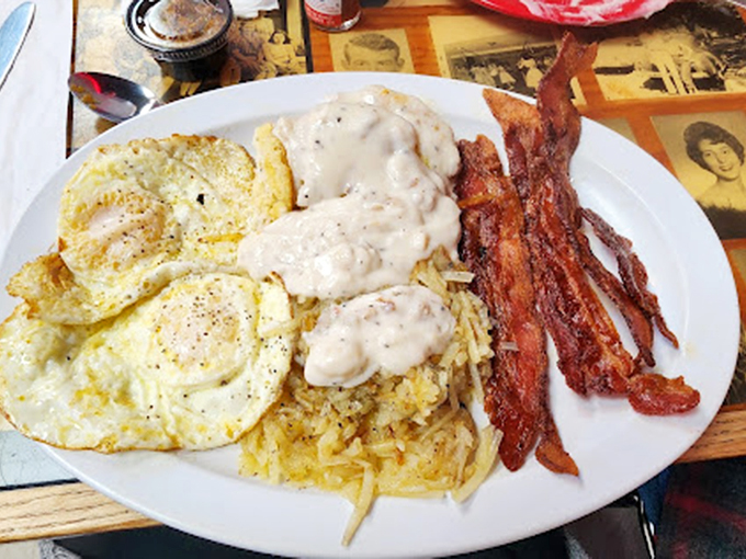 Breakfast nirvana achieved: eggs sunny-side up, hash browns smothered in country gravy, and bacon that would make a vegetarian question their life choices.