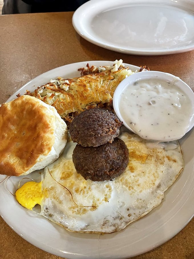 The breakfast trinity: golden eggs, crispy hash browns, and a biscuit so fluffy it practically hovers above the plate.