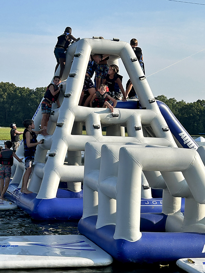 The inflatable climbing tower becomes a temporary mountain to conquer, where success is measured in laughter and the inevitable splash.