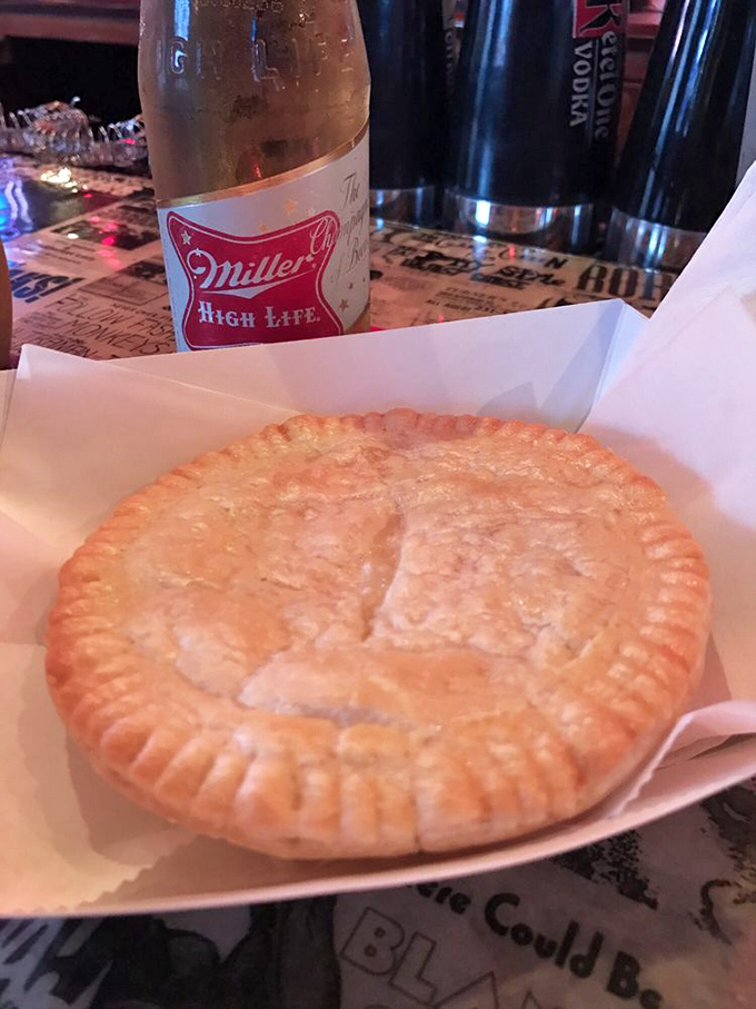 The humble meat pie sits proudly alongside a Miller High Life—proof that sometimes life's greatest pleasures come in simple, flaky packages.