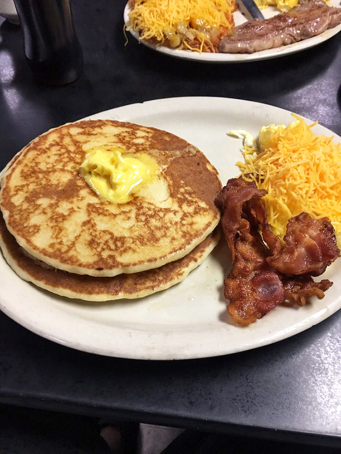 Golden pancakes with a melting pat of butter, crispy bacon, and cheese-topped hashbrowns&mdash;the holy trinity of breakfast that makes mornings worth facing.