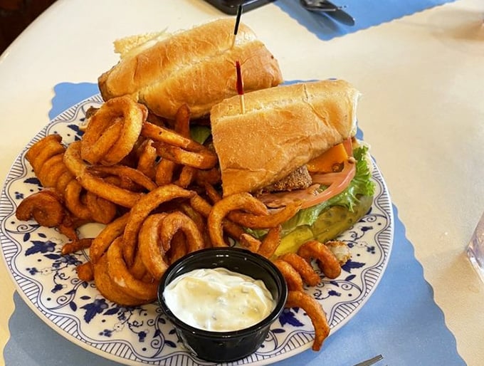 A sandwich feast that puts sad desk lunches to shame. Those curly fries deserve their own fan club, curling around the plate like they own the place.