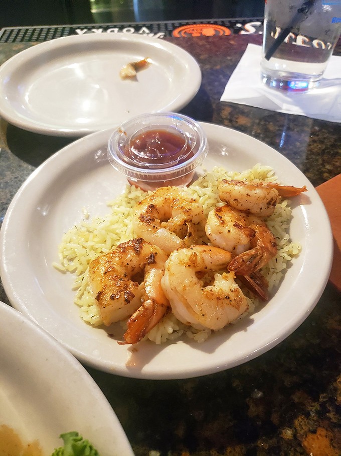 Plump shrimp perched atop buttery rice like treasures from a tastier ocean. That cocktail sauce isn't just condiment&mdash;it's an invitation to dive deeper.