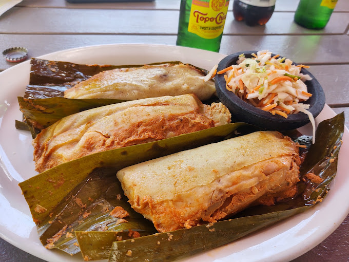 A plate of tamales with curtido and traditional sides &ndash; proving that true luxury isn't about white tablecloths but about food that speaks directly to your soul.