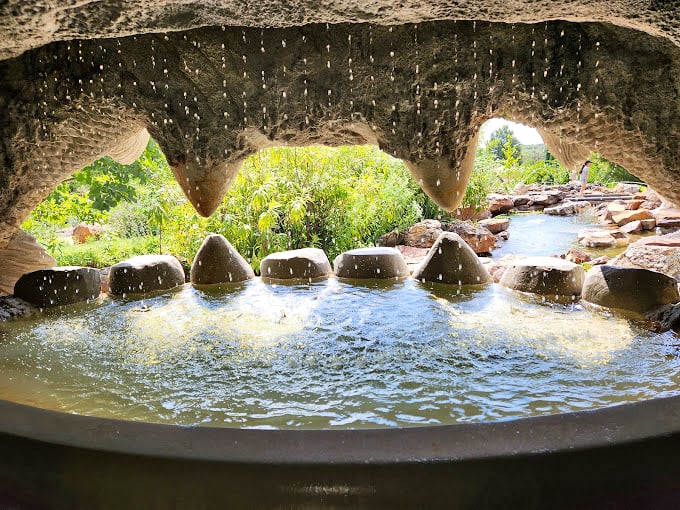 Peek through this stone archway and discover a secret water world where droplets create a mesmerizing curtain between you and the garden beyond.