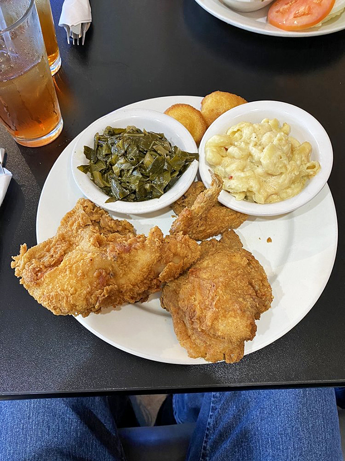 Collard greens and mac and cheese flanking fried chicken that deserves its own theme song. This plate has "Sunday dinner at grandma's" written all over it.