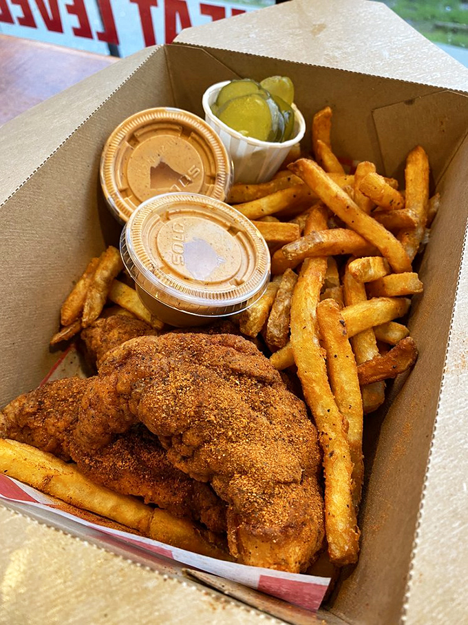 The architecture of a perfect meal: crispy chicken, seasoned fries, cool pickles, and those magical dipping sauces that somehow make everything better.