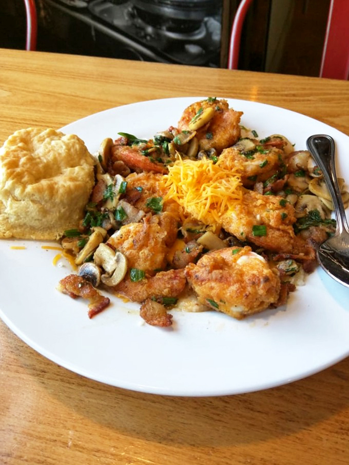 A biscuit stands guard over this battlefield of flavors where shrimp, cheese, and grits wage delicious war on your diet plans.