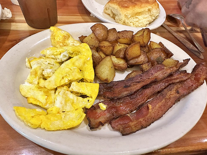 The breakfast trinity: fluffy scrambled eggs, crispy bacon, and potatoes that somehow manage to be both crisp and tender. Morning salvation on a plate.