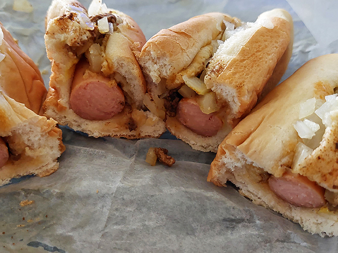 The cross-section reveals the architecture of perfection: steamed bun, snappy dog, fine-ground chili, and diced onions in harmonious balance.