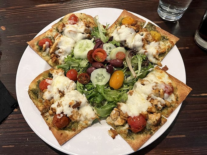 A flatbread that refuses to be background food. Fresh greens and colorful tomatoes create a garden party atop melted cheese and savory chicken.
