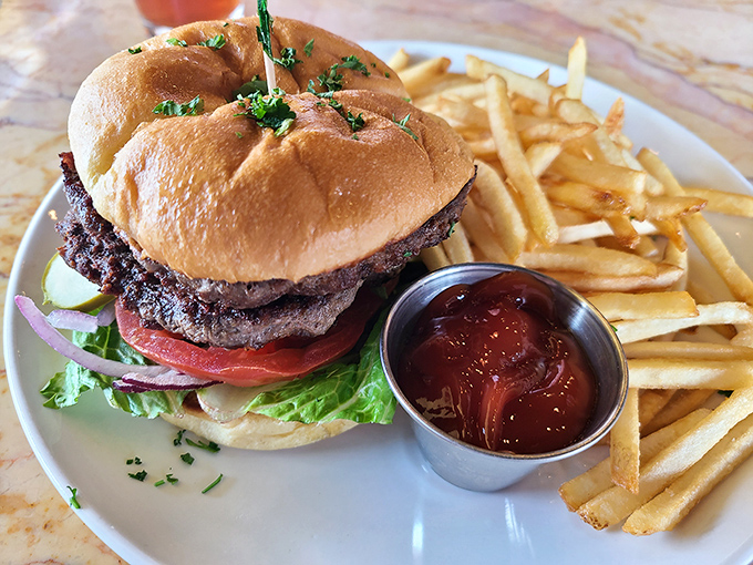 A burger that demands both hands and your undivided attention, with fries standing at attention like golden soldiers guarding flavor country.