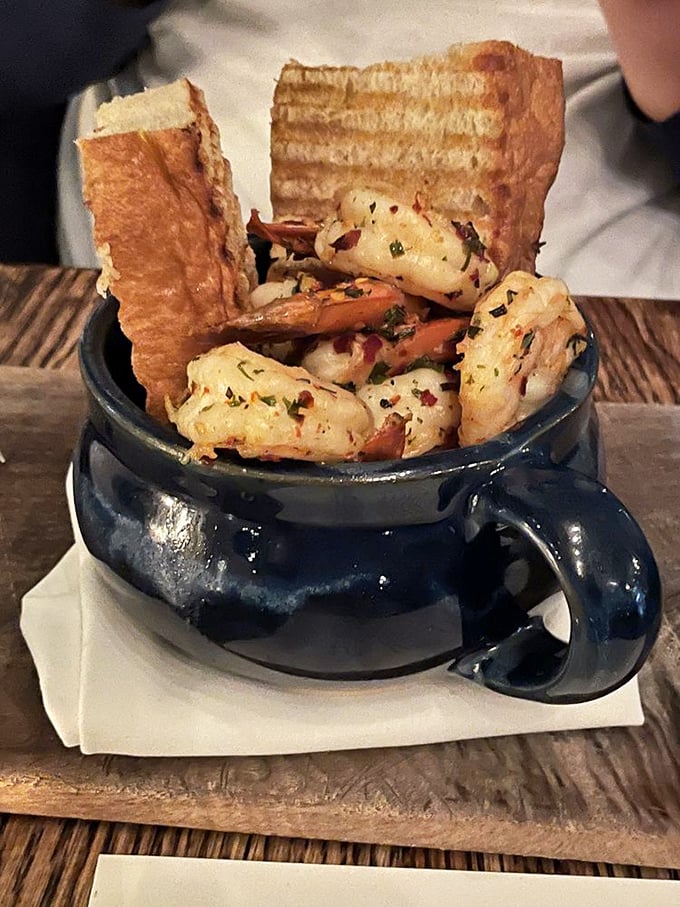 Garlic shrimp nestled in a navy blue mug with grilled bread soldiers standing at attention, ready for their delicious duty.