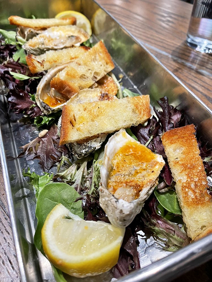 Char-grilled oysters lounging on a bed of mixed greens. These briny treasures on toast points are what food photographers dream about at night.