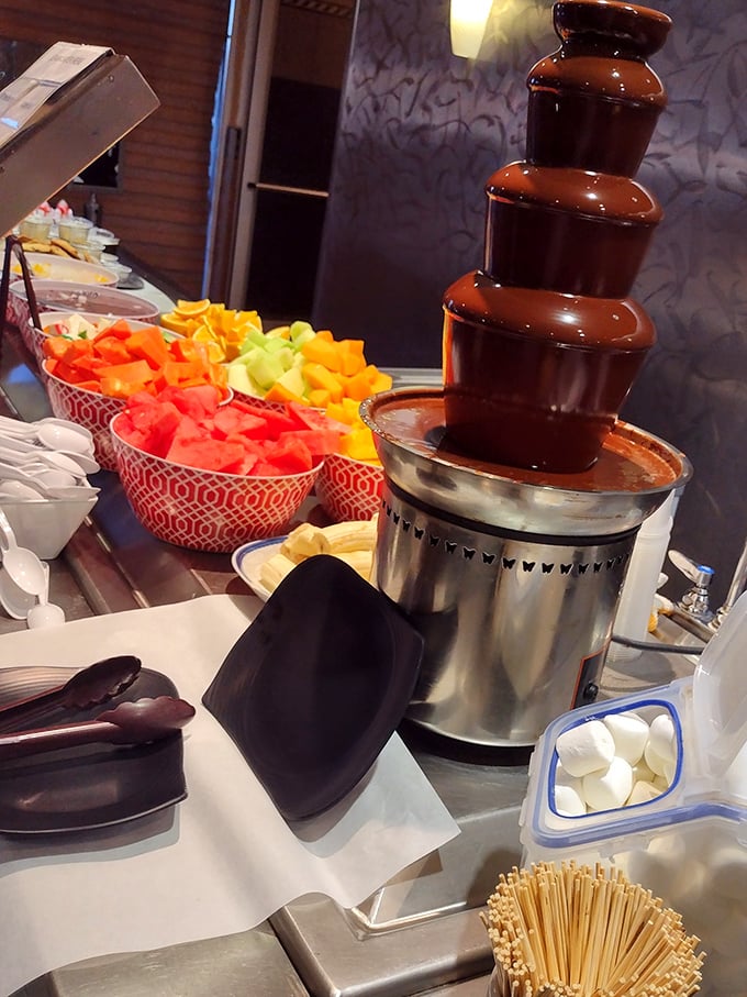 The chocolate fountain stands like a monument to indulgence, surrounded by fresh fruit waiting for their warm chocolate bath. Marshmallows standing by.