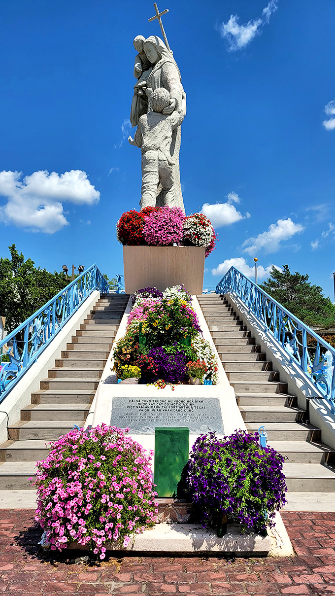 The Congregation of the Mother of the Redeemer statue stands tall amid vibrant flowers. A colorful testament to Carthage's Vietnamese cultural influence.