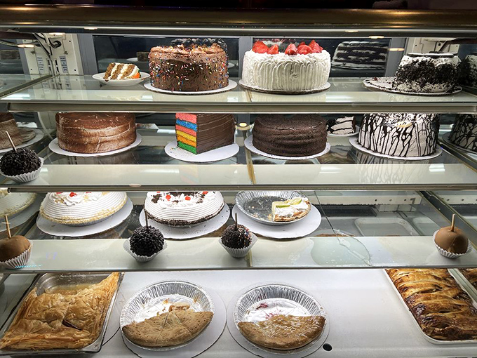 The dessert case: where diets go to die gloriously. Each cake stands tall like a sugary skyscraper of temptation.