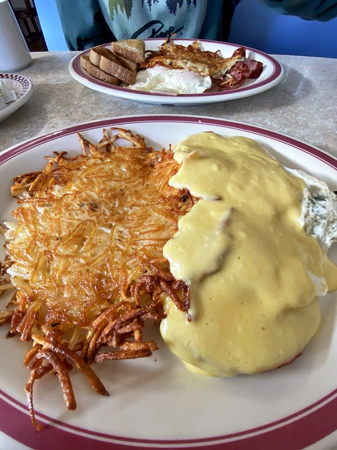 Country gravy cascading over crispy hash browns—a breakfast waterfall that would make Niagara Falls jealous.