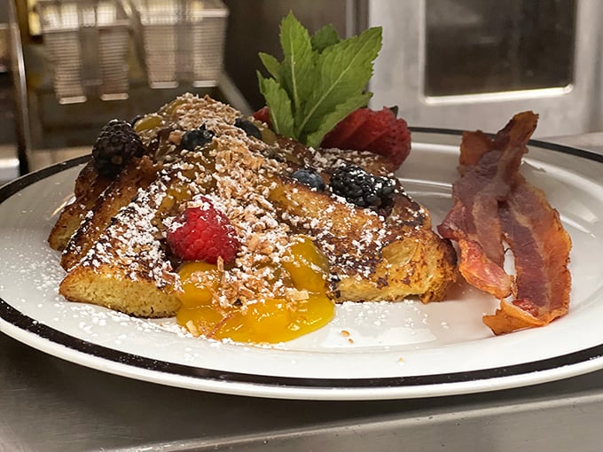 French toast that belongs in the breakfast hall of fame. Berries, powdered sugar, and that crispy bacon side make morning worth facing.