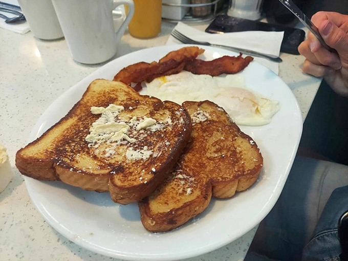 French toast so perfectly golden it belongs in Fort Knox, dusted with powdered sugar like the first hint of Florida frost.