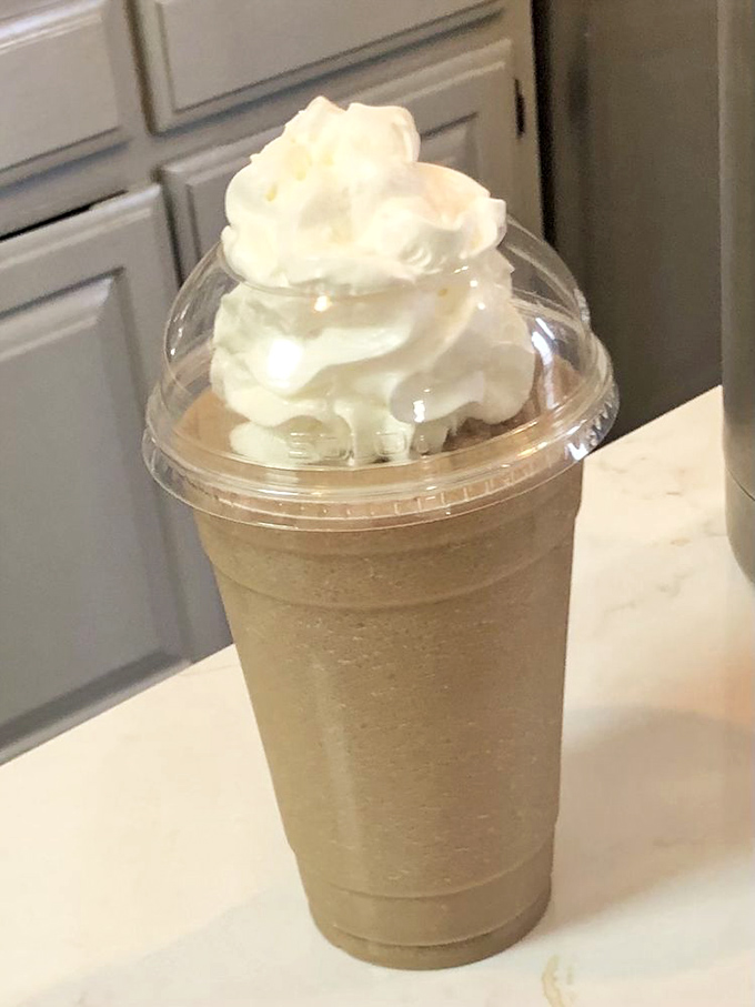 The frozen cappuccino arrives like a cool mountain of caffeinated bliss, topped with a cloud of whipped cream that defies gravity and good sense.