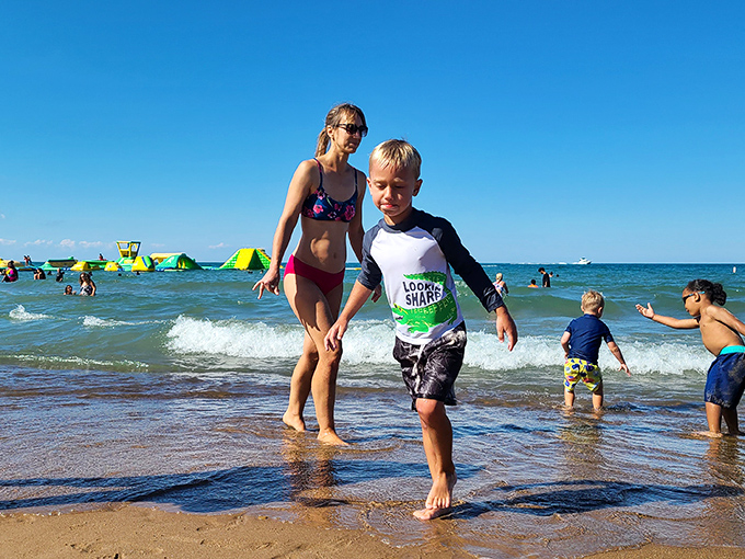 Shoreline joy in its purest form. Children test the waters while the WhoaZone beckons in the background&mdash;a perfect introduction to Lake Michigan's refreshing embrace.