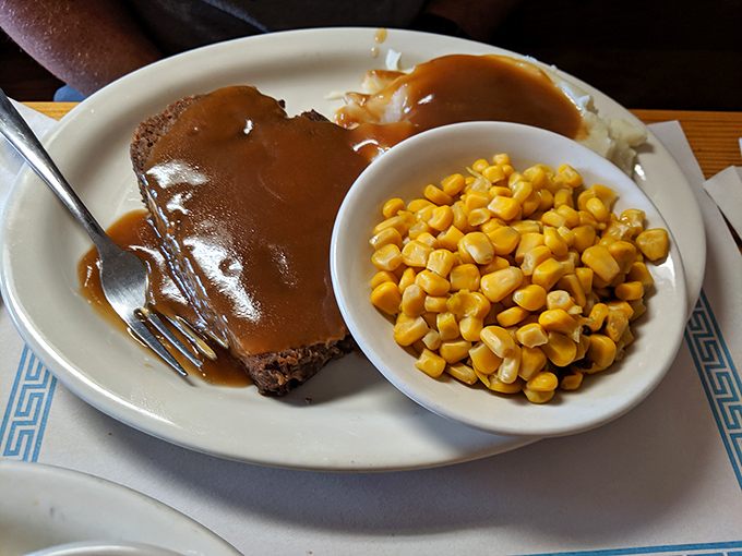A slice of meatloaf swimming in rich brown gravy alongside sweet corn &ndash; proof that midwestern cuisine isn't fancy, but it knows how to hug your soul.