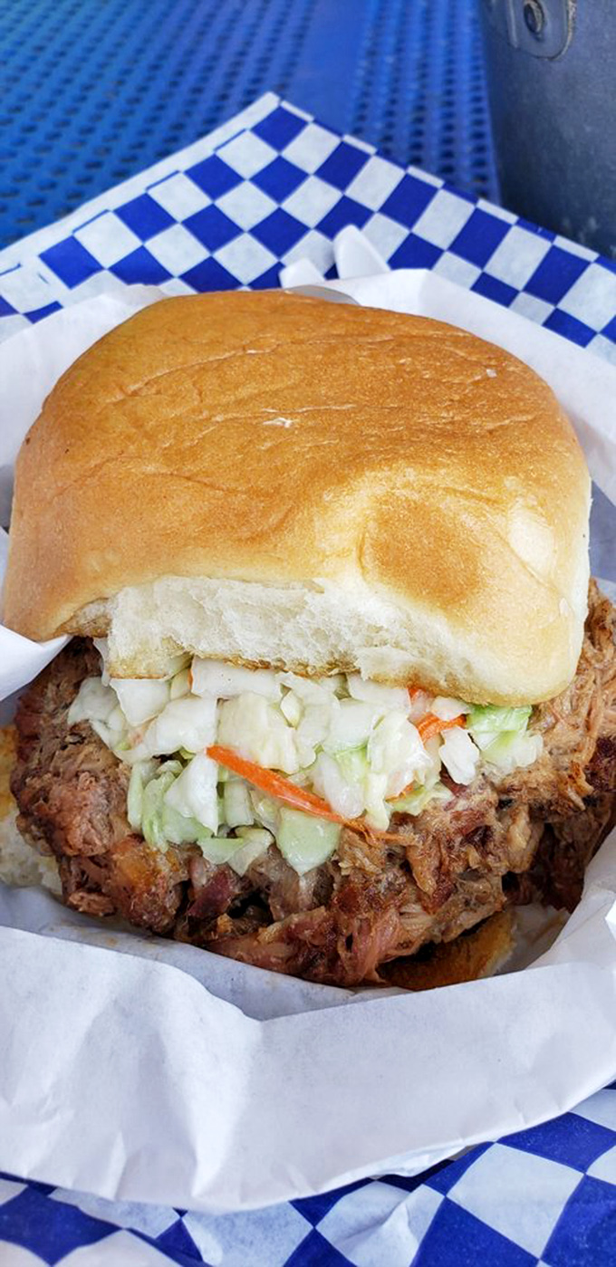 This isn't just a sandwich; it's an architectural marvel of smoke-kissed pork and crisp slaw that requires both hands and your full attention.