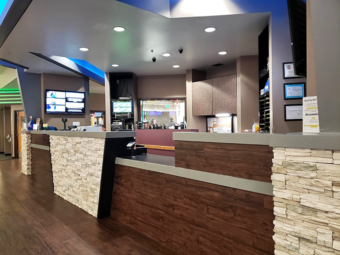 The modern reception area blends stone and wood elements, proving bowling alleys have evolved beyond the sticky-floor era.