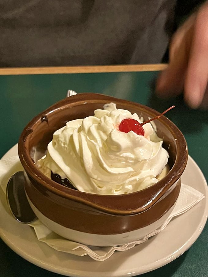 A classic sundae served in a rustic brown crock, topped with whipped cream and a cherry&mdash;proof that sometimes the simplest desserts are the most satisfying.
