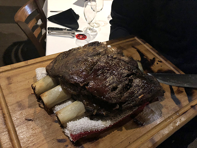 Bone-in meat presented on a wooden board—primal, theatrical, and absolutely worth the caveman jokes you'll make while devouring it.