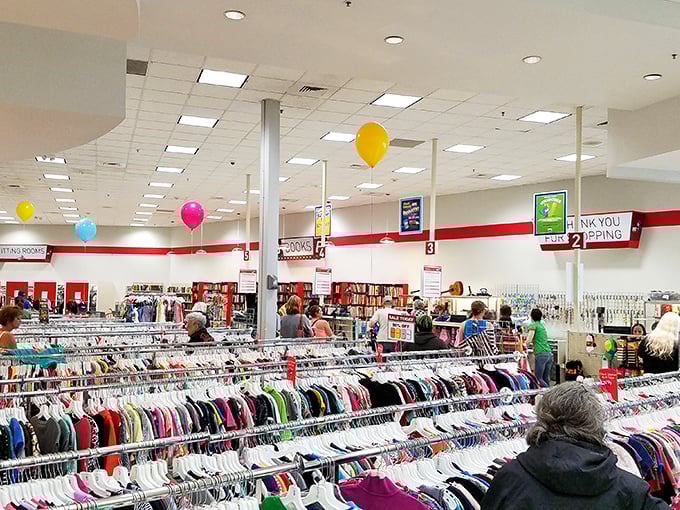 Serious shoppers navigate the clothing labyrinth with practiced precision, their carts filling with colorful possibilities under festive balloon decorations.