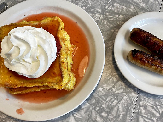 French toast reaching its final form&mdash;stuffed with cream filling and topped with powdered sugar, with sausage links standing guard against breakfast boredom.