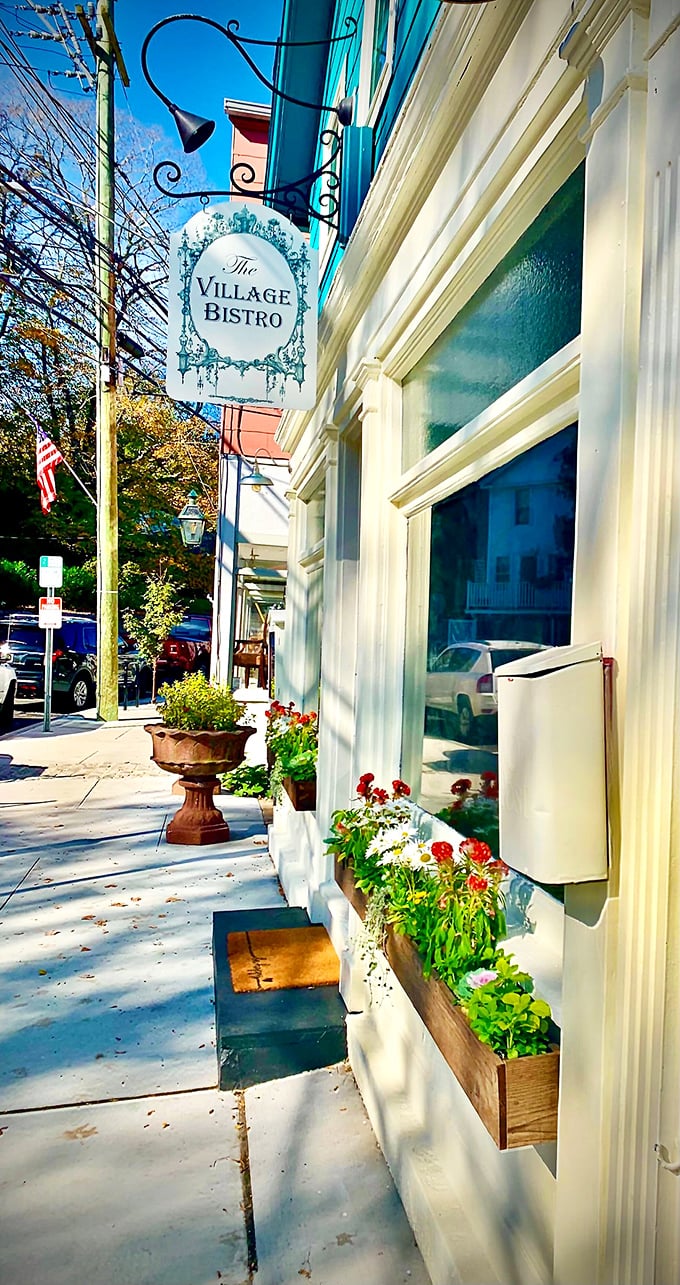 Colorful window boxes and a decorative hanging sign welcome you to a charming bistro while you walk down this sidewalk.