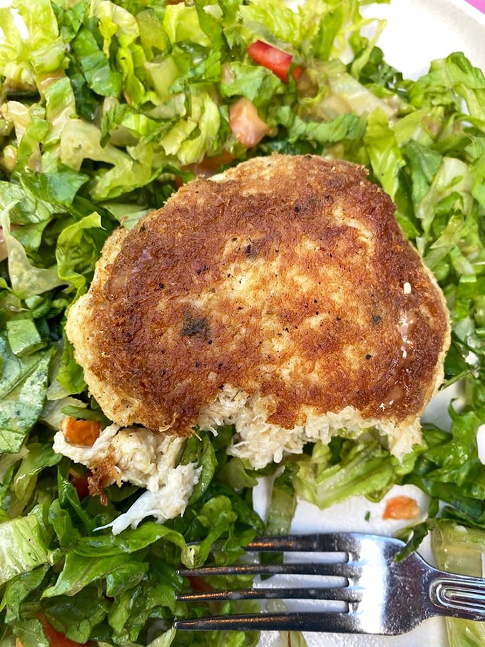 This golden-brown crab cake perched atop fresh greens is the Chesapeake Bay's gift to your lunch hour. Simple, elegant, and packed with flavor.