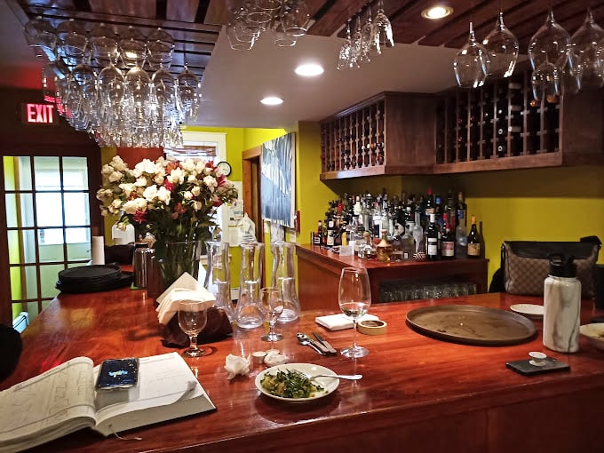 The bar at Moya isn't just where drinks are poured—it's where stories are exchanged, with wine glasses hanging like crystal stalactites ready for your next celebration.