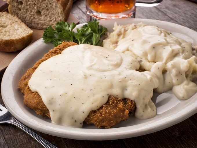 Chicken fried steak wearing its gravy coat like a comfortable old sweater. This isn't just comfort food&mdash;it's therapy on a plate.