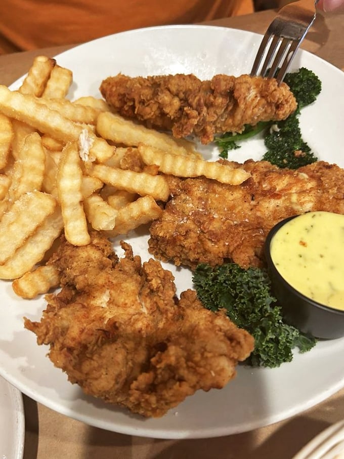 These golden-fried chicken tenders achieve that rare balance: a satisfyingly crunchy exterior giving way to juicy meat within, accompanied by fries that demand to be noticed.
