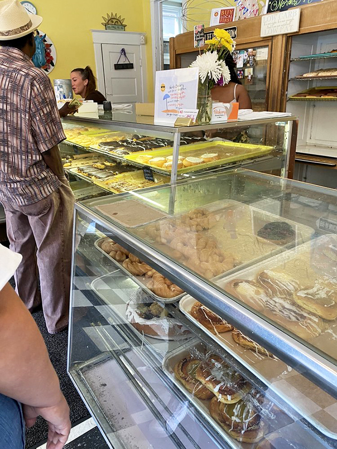 A peek behind the bakery counter where magic happens daily. That chalkboard and those ceiling fans have witnessed countless moments of pure sugar-induced joy.