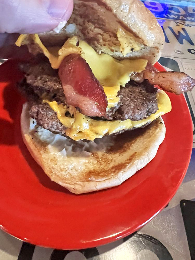 The top bun serves as a throne for what lies beneath: a masterpiece of beef, bacon, and cheese that demands respect.